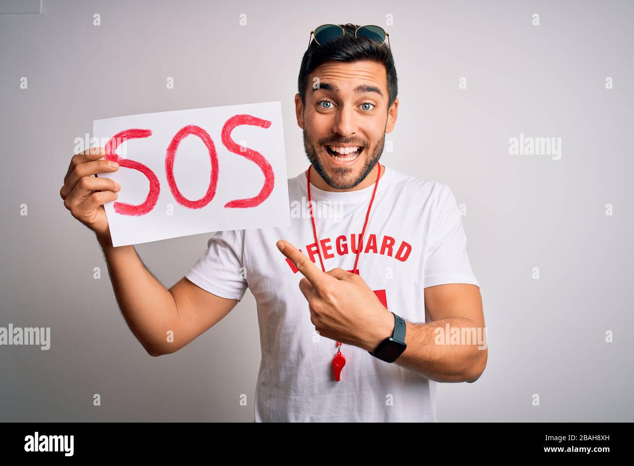 Young lifeguard man with beard wearing whistle holding paper with sos ...