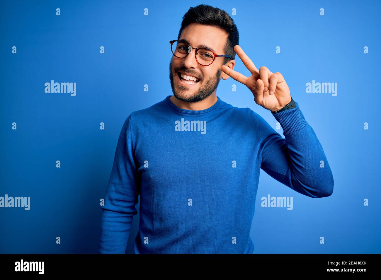Young handsome man with beard wearing casual sweater and glasses over ...