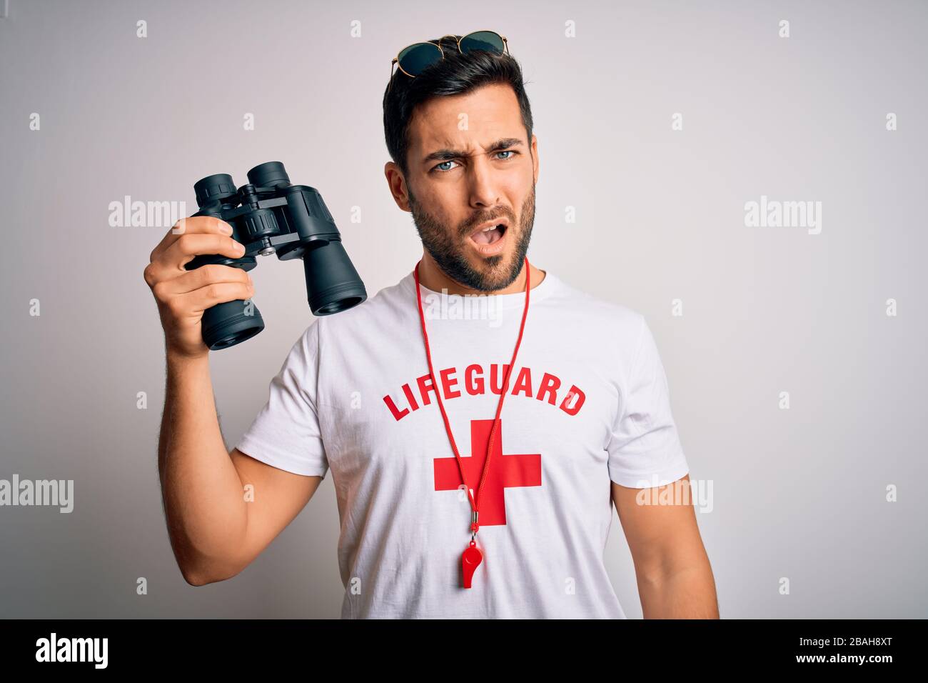 Young lifeguard man with beard wearing t-shirt with red cross and ...