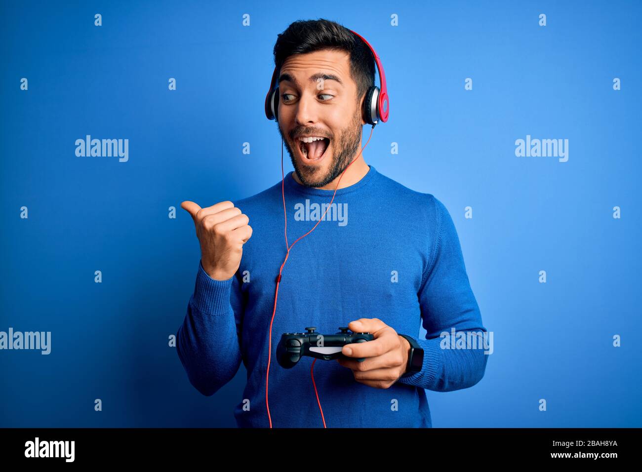 Young handsome gamer man with beard playing video game using joystick ...