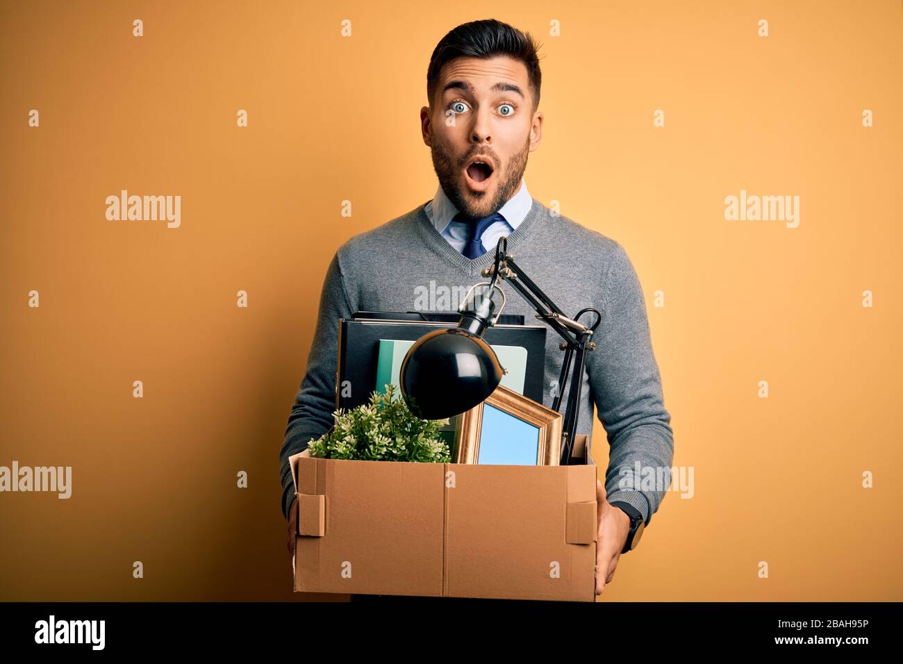 Young business man holding office box being fired from job over yellow ...