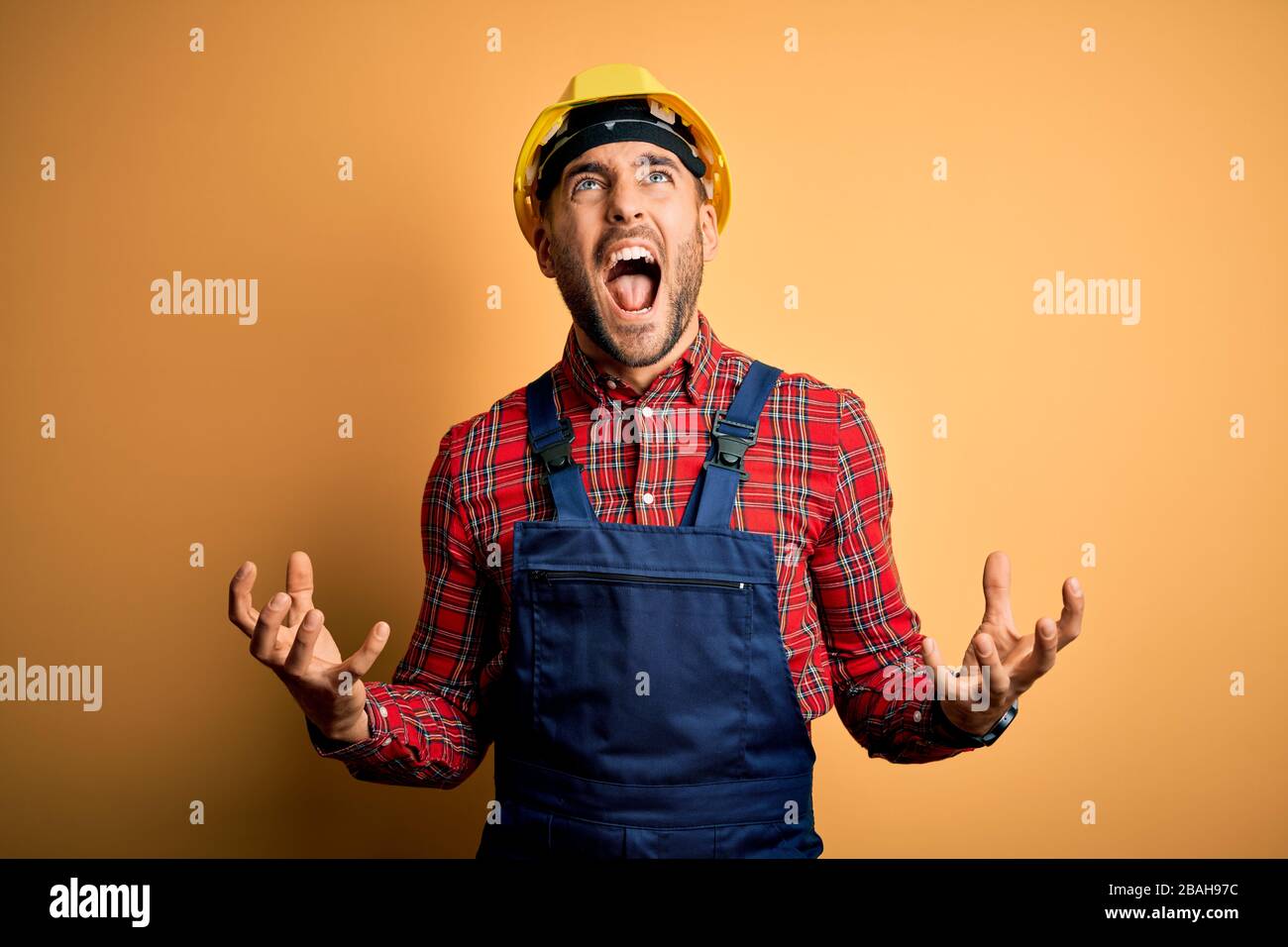 Young builder man wearing construction uniform and safety helmet over ...