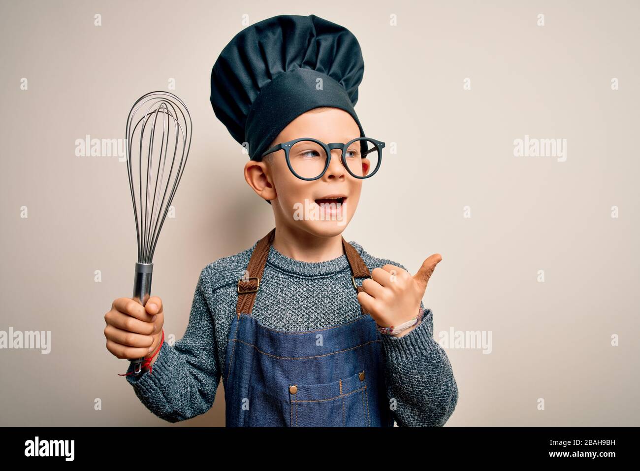 Young little caucasian cook kid wearing chef uniform and hat using ...