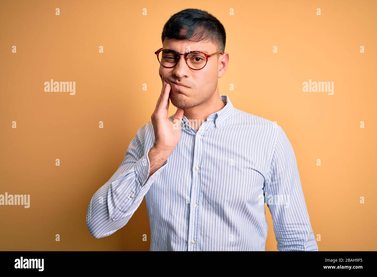 Young handsome hispanic business man wearing nerd glasses over yellow ...