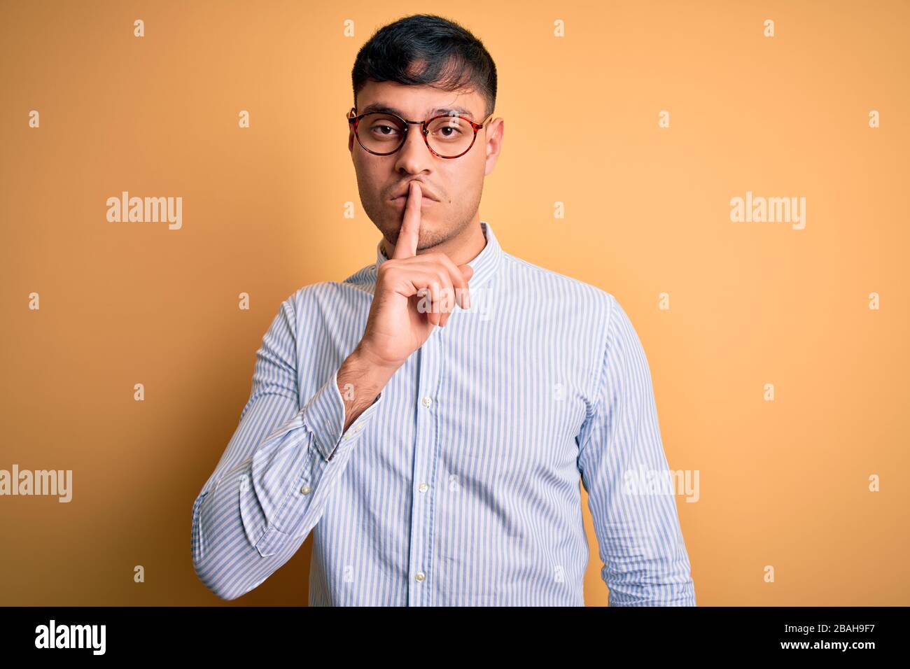 Young handsome hispanic business man wearing nerd glasses over yellow ...