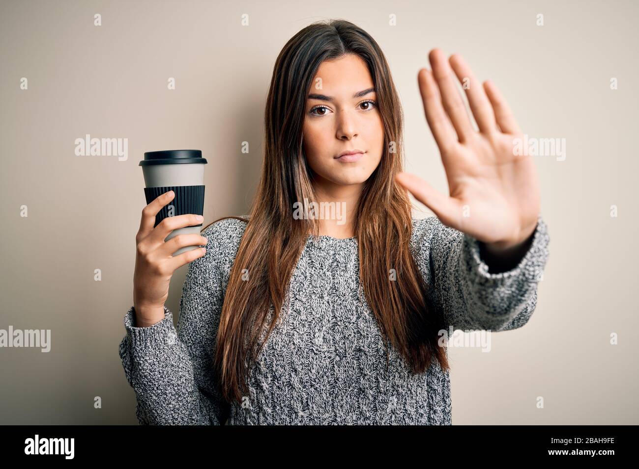 Young beautiful girl drinking cup of coffee standing over isolated ...