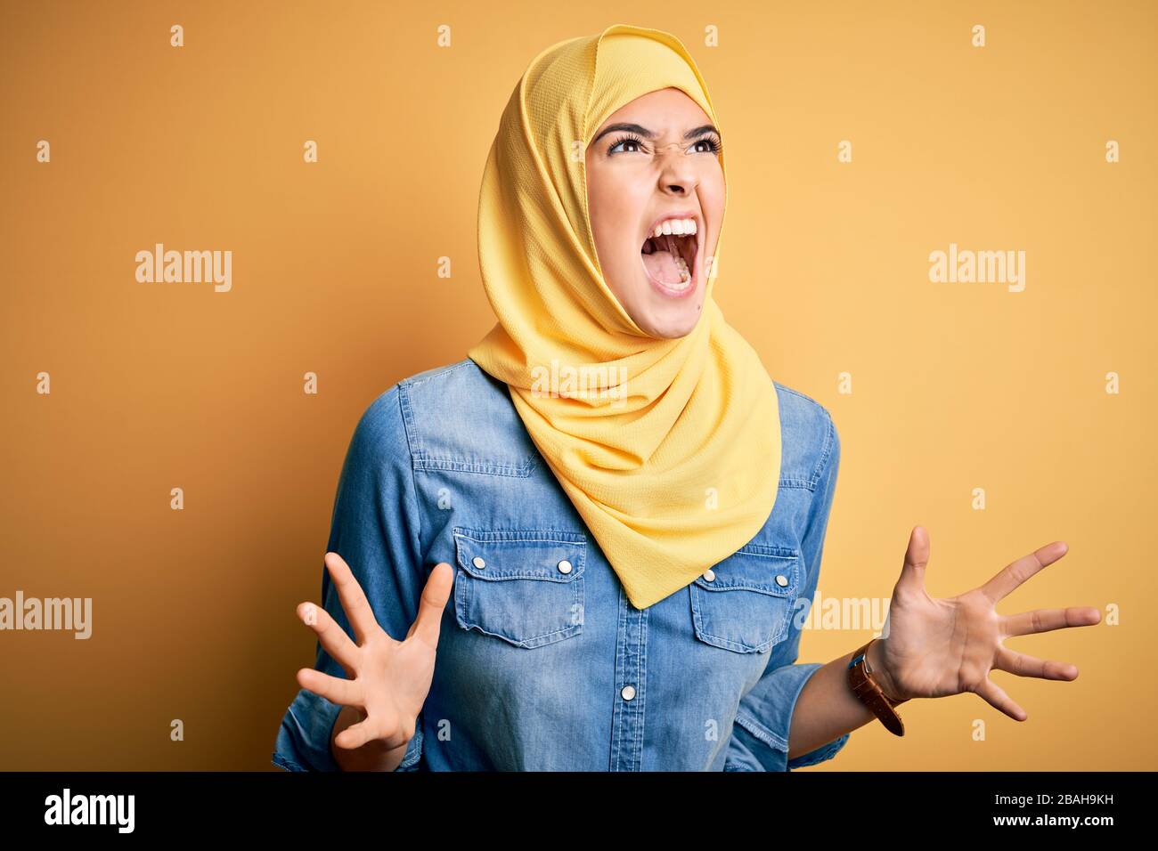 Young beautiful girl wearing muslim hijab standing over isolated yellow ...