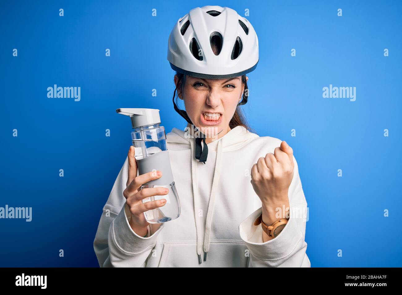 Young beautiful redhead cyclist woman wearing bike helmet drinkjng ...