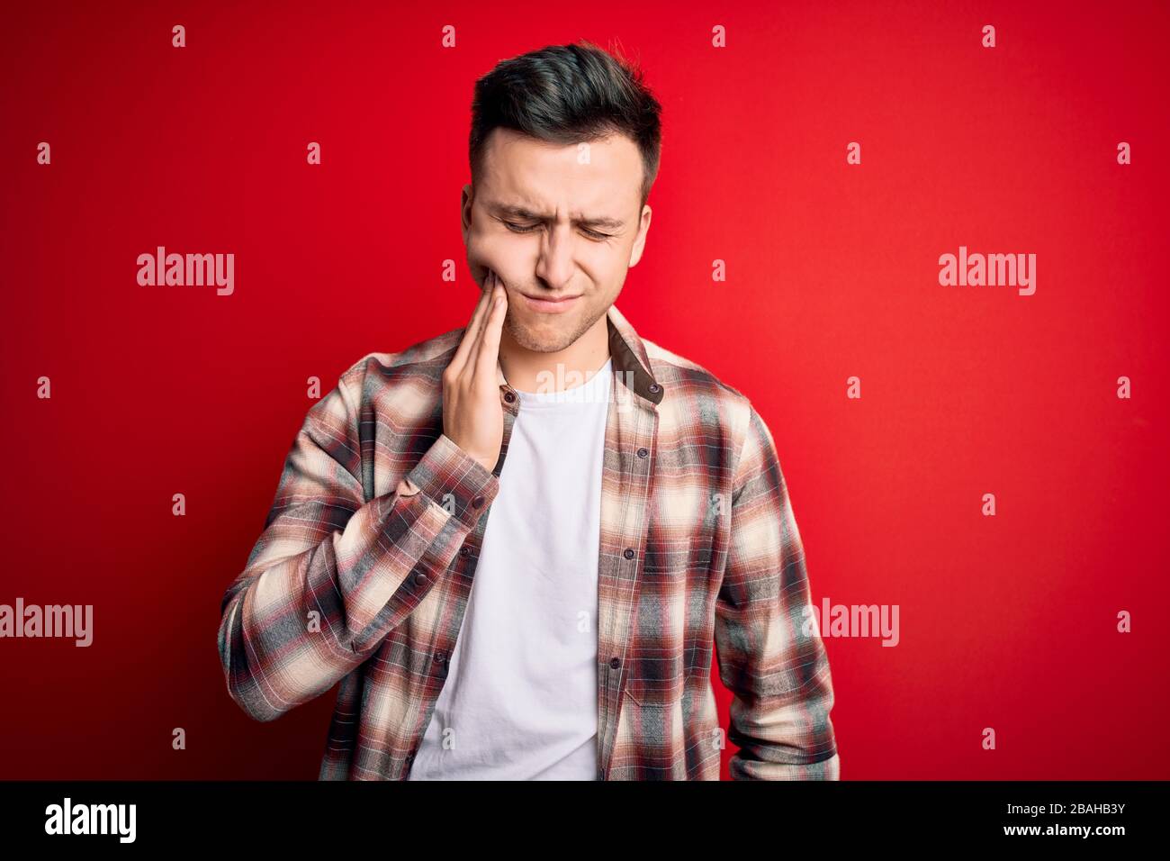 Young handsome caucasian man wearing casual modern shirt over red ...