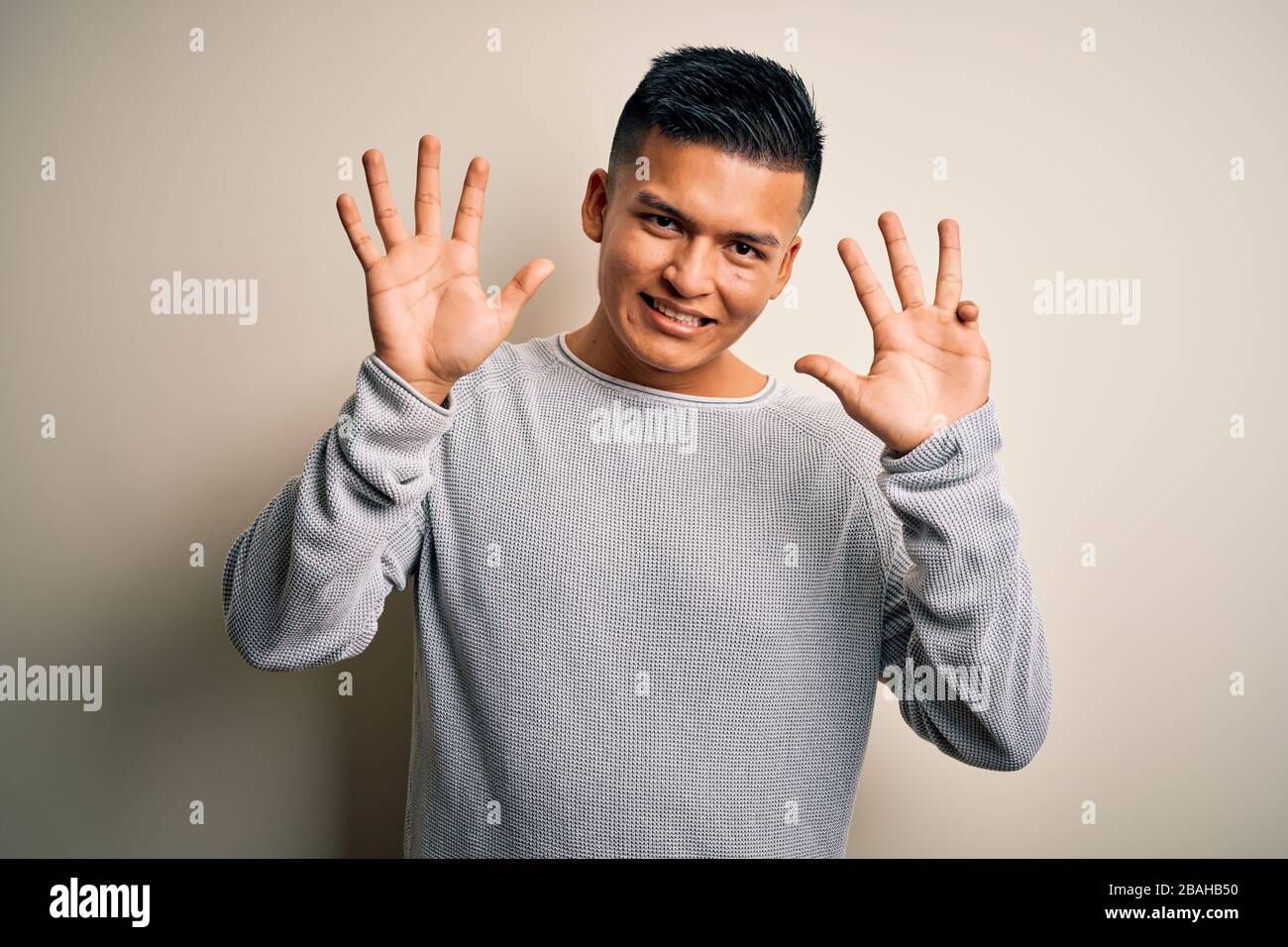 Young handsome latin man wearing casual sweater standing over isolated ... Young handsome latin man wearing casual sweater standing over isolated ...