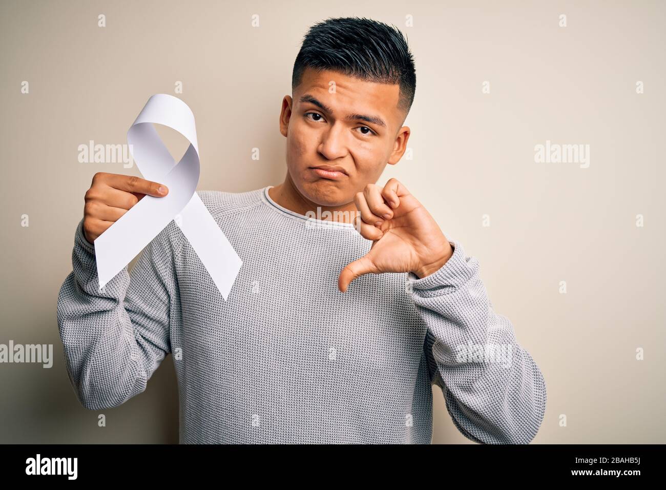 Young latin man holding white cancer ribbon supporting stop women ...