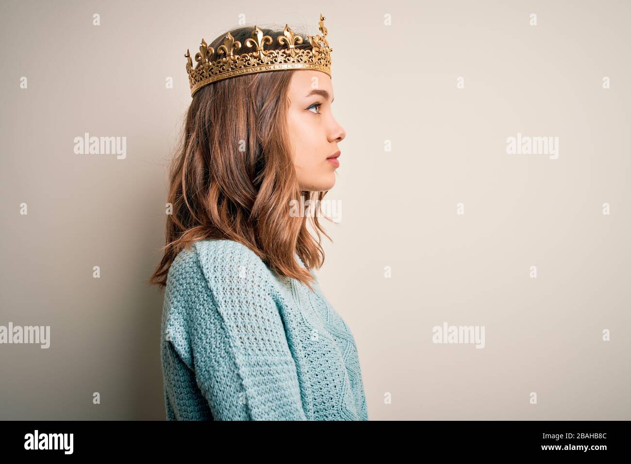 Young blonde girl wearing queen golden crown over isolated background ...