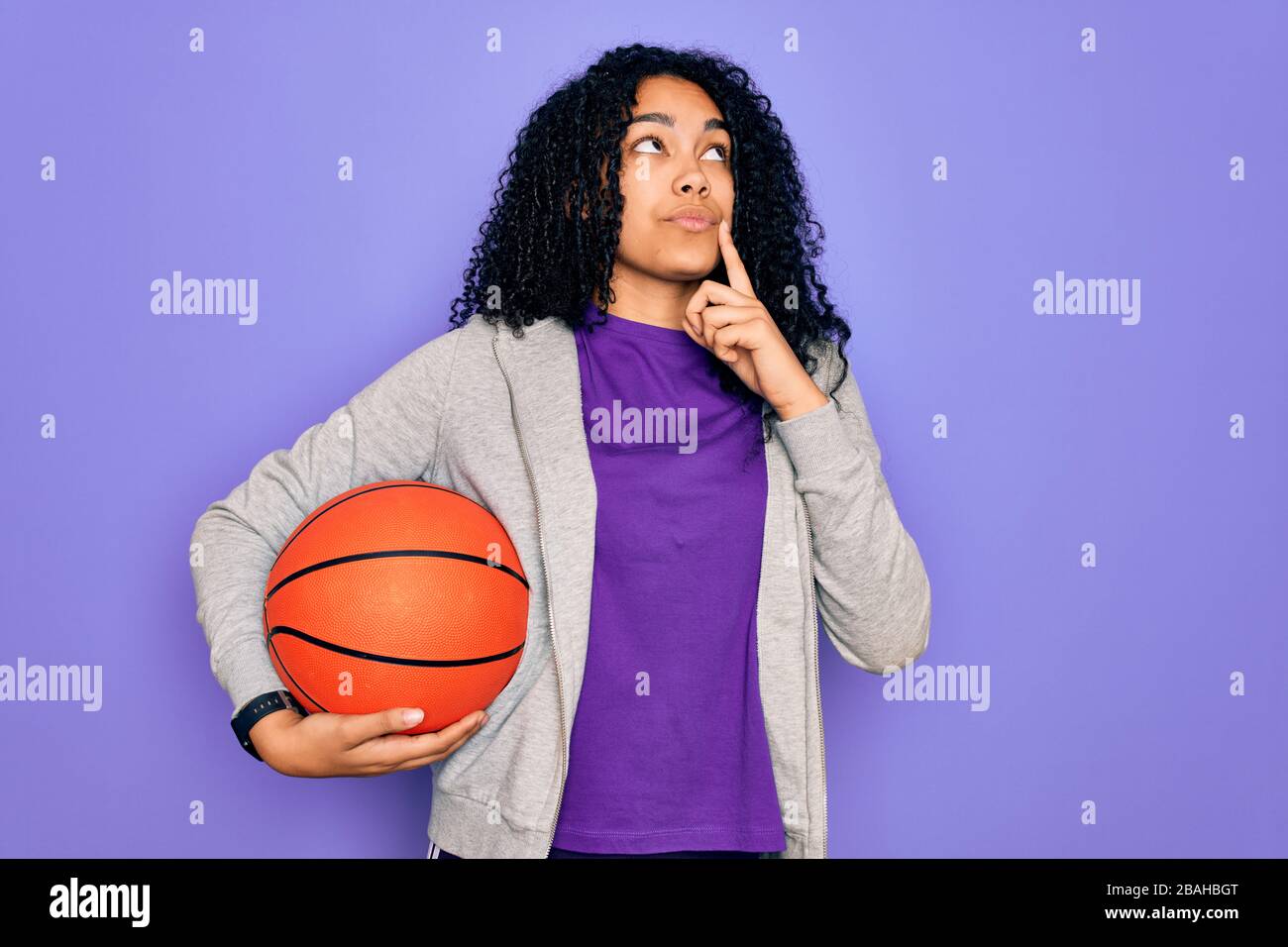 African american curly sportswoman doing sport holding basketball ball ...