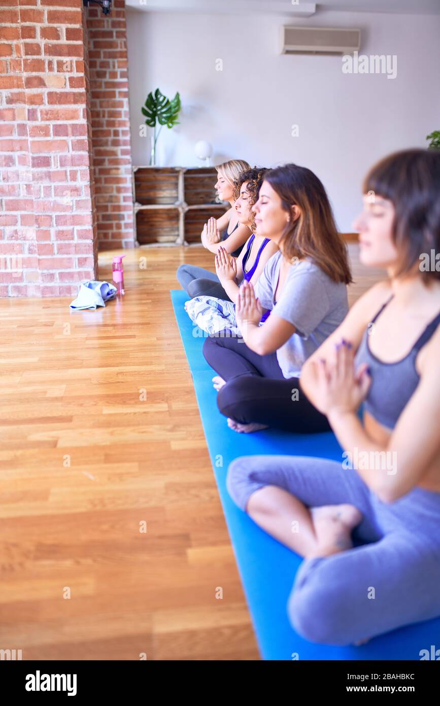 Young beautiful group of sportswomen smiling happy practicing yoga ...