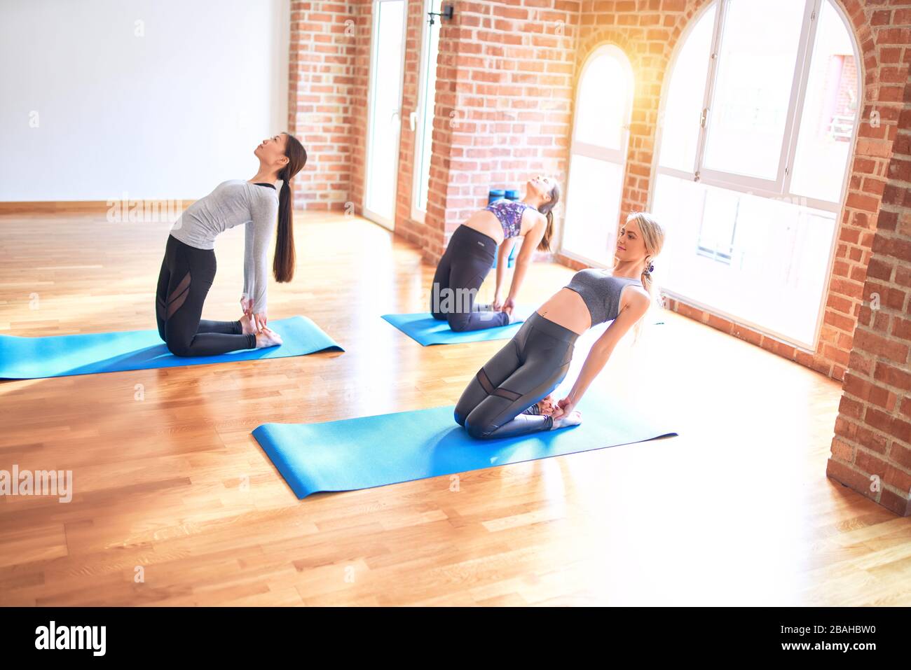 Young beautiful group of sportswomen smiling happy practicing yoga ...
