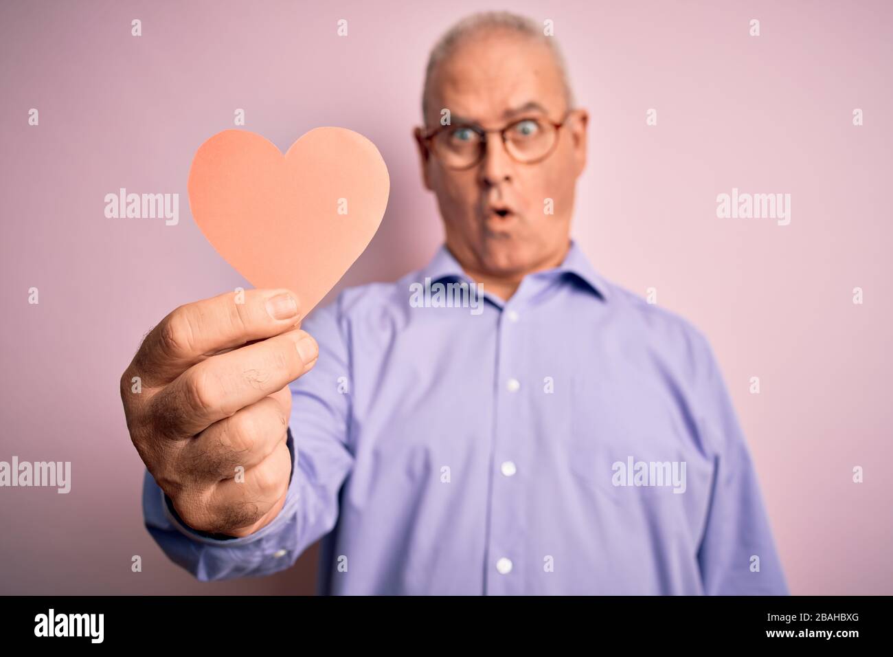 Middle age hoary romantic man holding red paper heart shape over ...