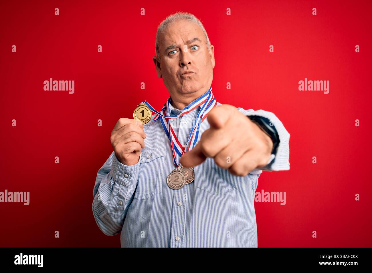 Middle age hoary champion man wearing medals standing over isolated red ...