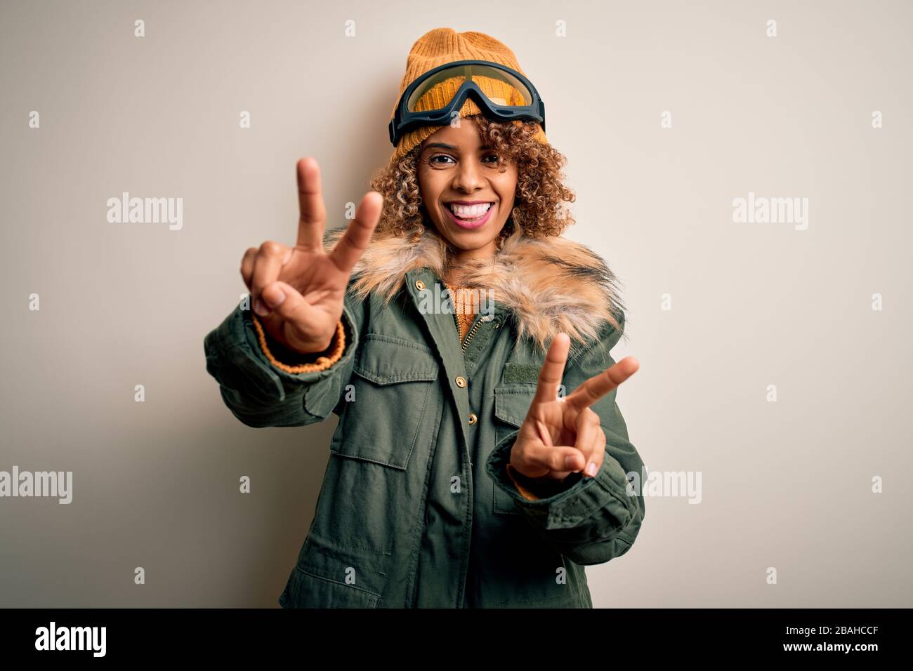 Young african american skier woman with curly hair wearing snow ...