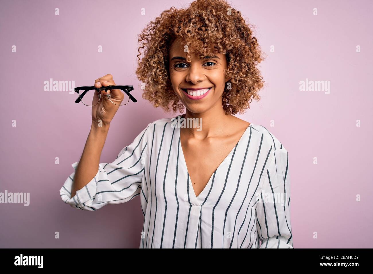 African american optical woman with curly hair holding glasses over ...