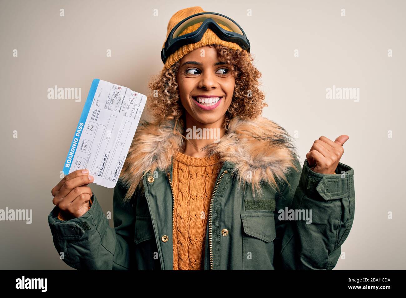 Young african american tourist woman wearing ski goggles holding plane ...