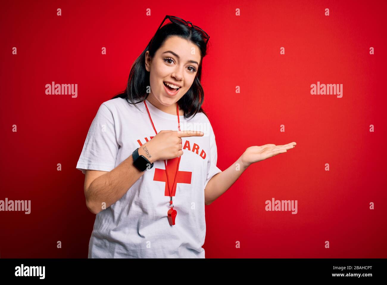 Young lifeguard woman wearing secury guard equipent over red background ...
