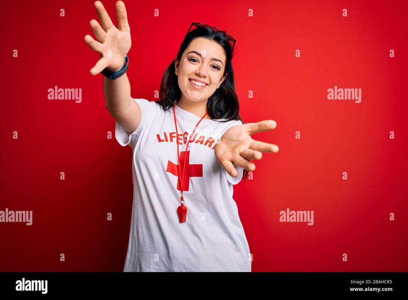 Young lifeguard woman wearing secury guard equipent over red background ...