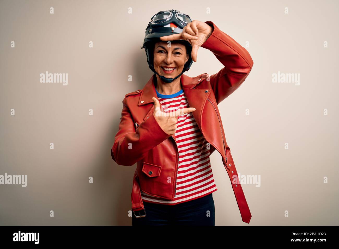 Middle age motorcyclist woman wearing motorcycle helmet and jacket over ...