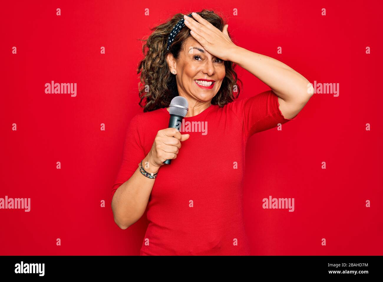 Middle age senior singer woman singing using music microphone over red ...
