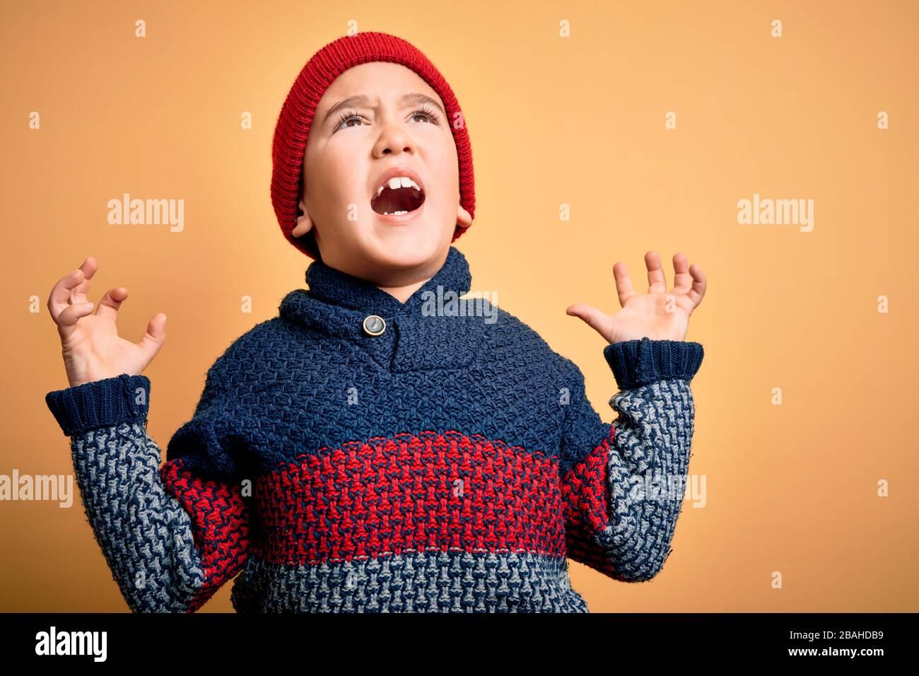 Young little boy kid wearing wool cap and winter sweater over yellow ...
