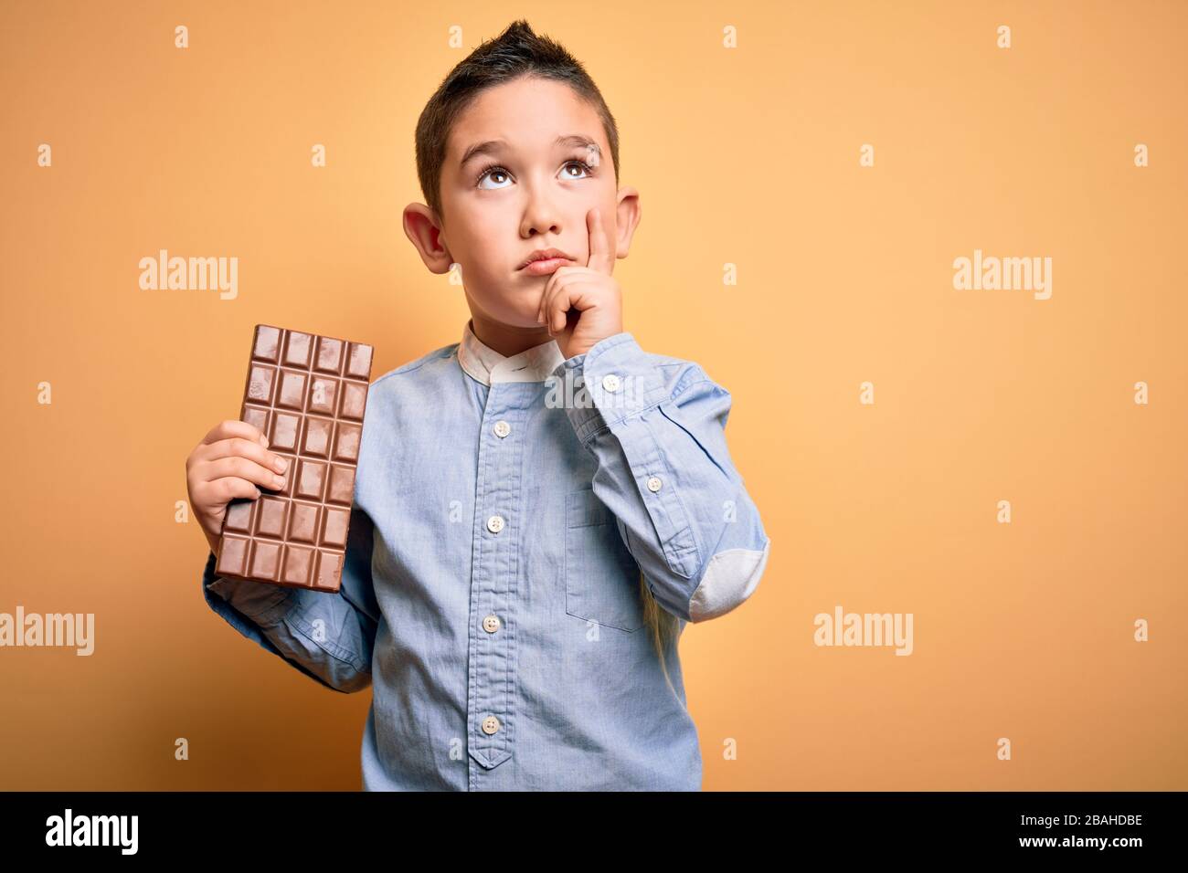 Young little boy kid eating sweet chocolate bar for dessert over ...