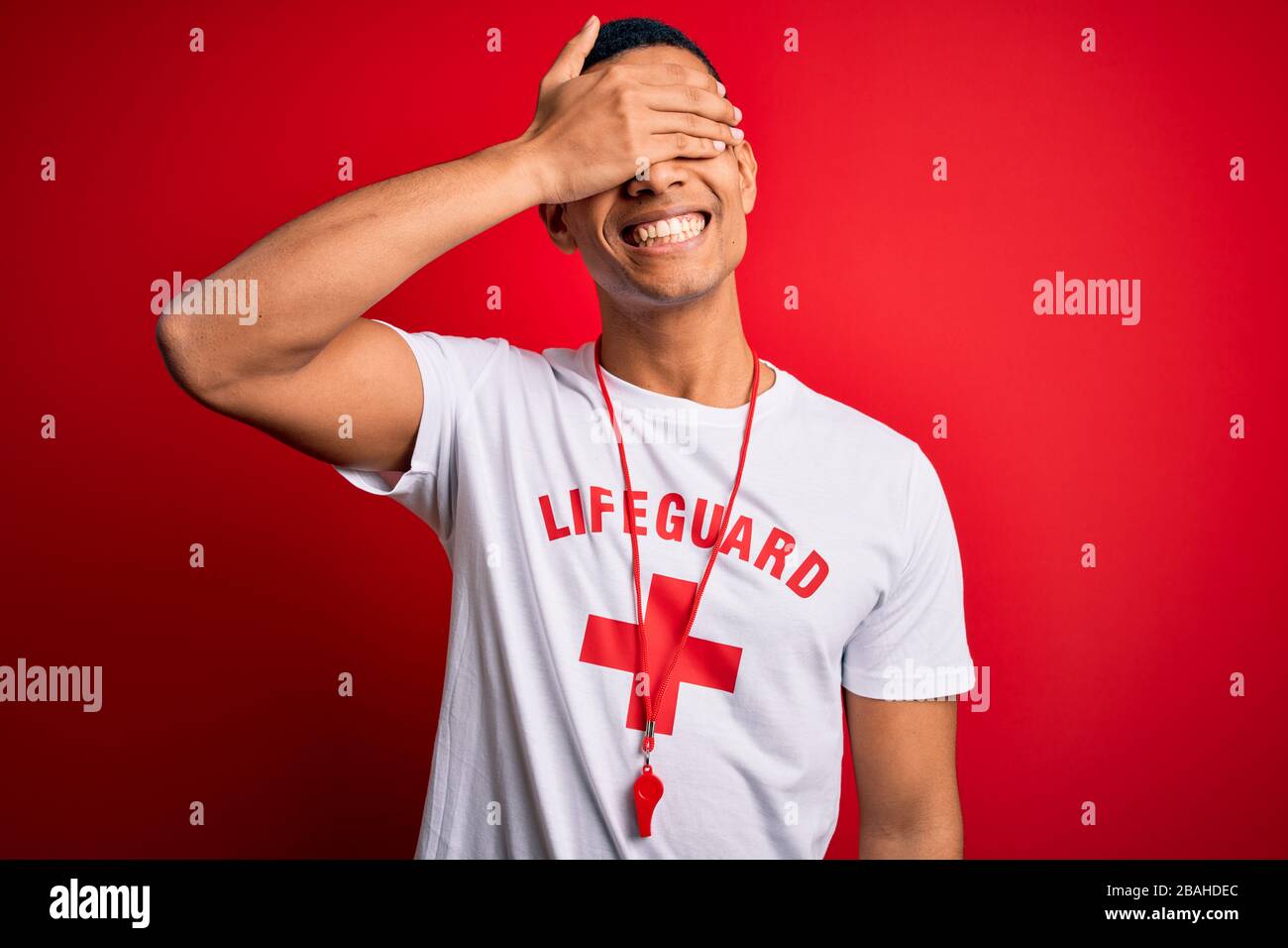 Young handsome african american lifeguard man wearing t-shirt with red ...