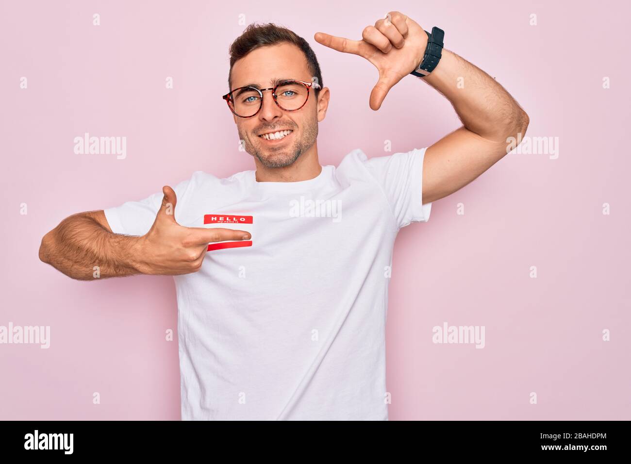 Handsome man with blue eyes wearing sticker with hello my name is ...