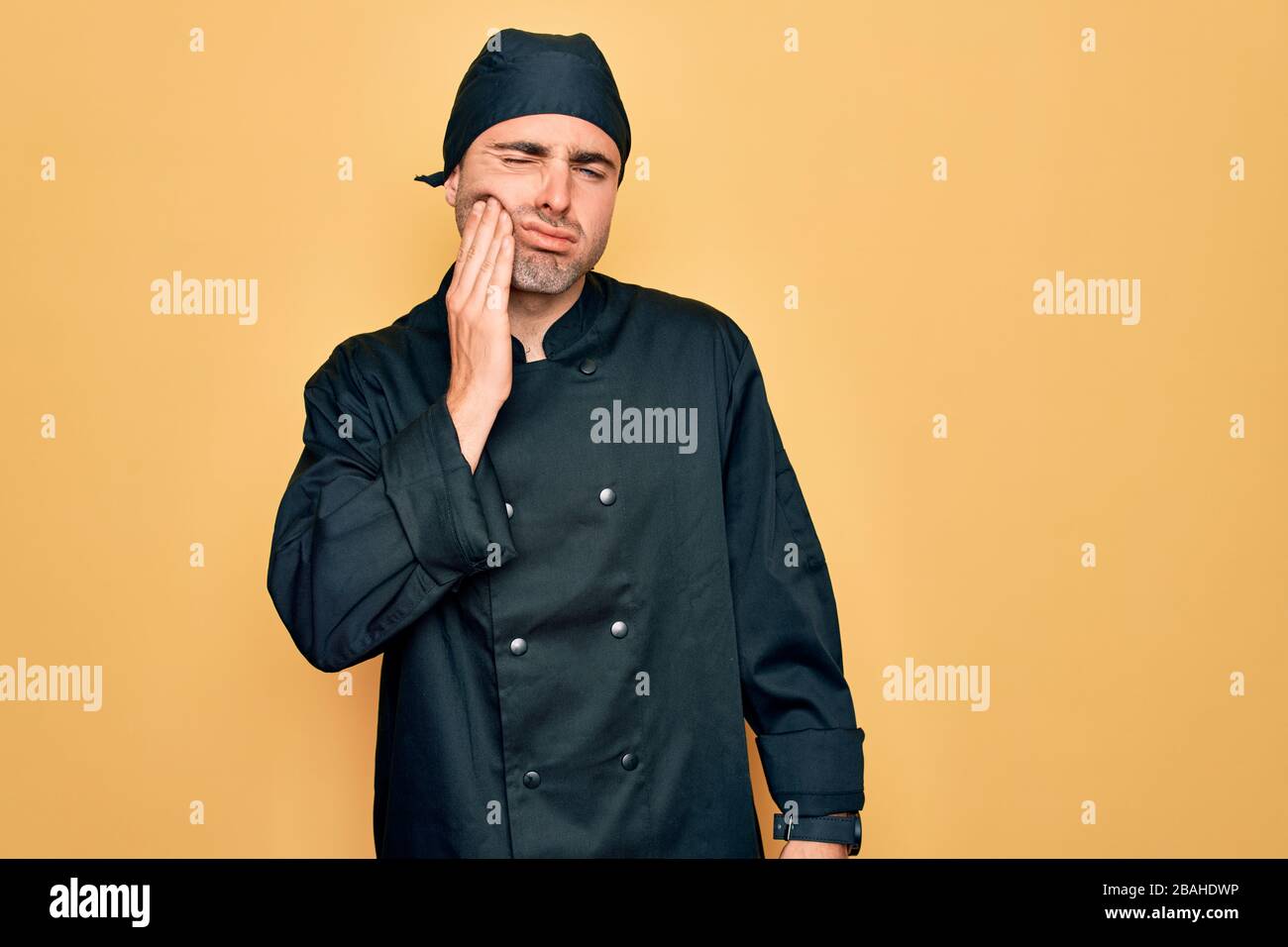 Young handsome cooker man with blue eyes wearing uniform and hat over ...