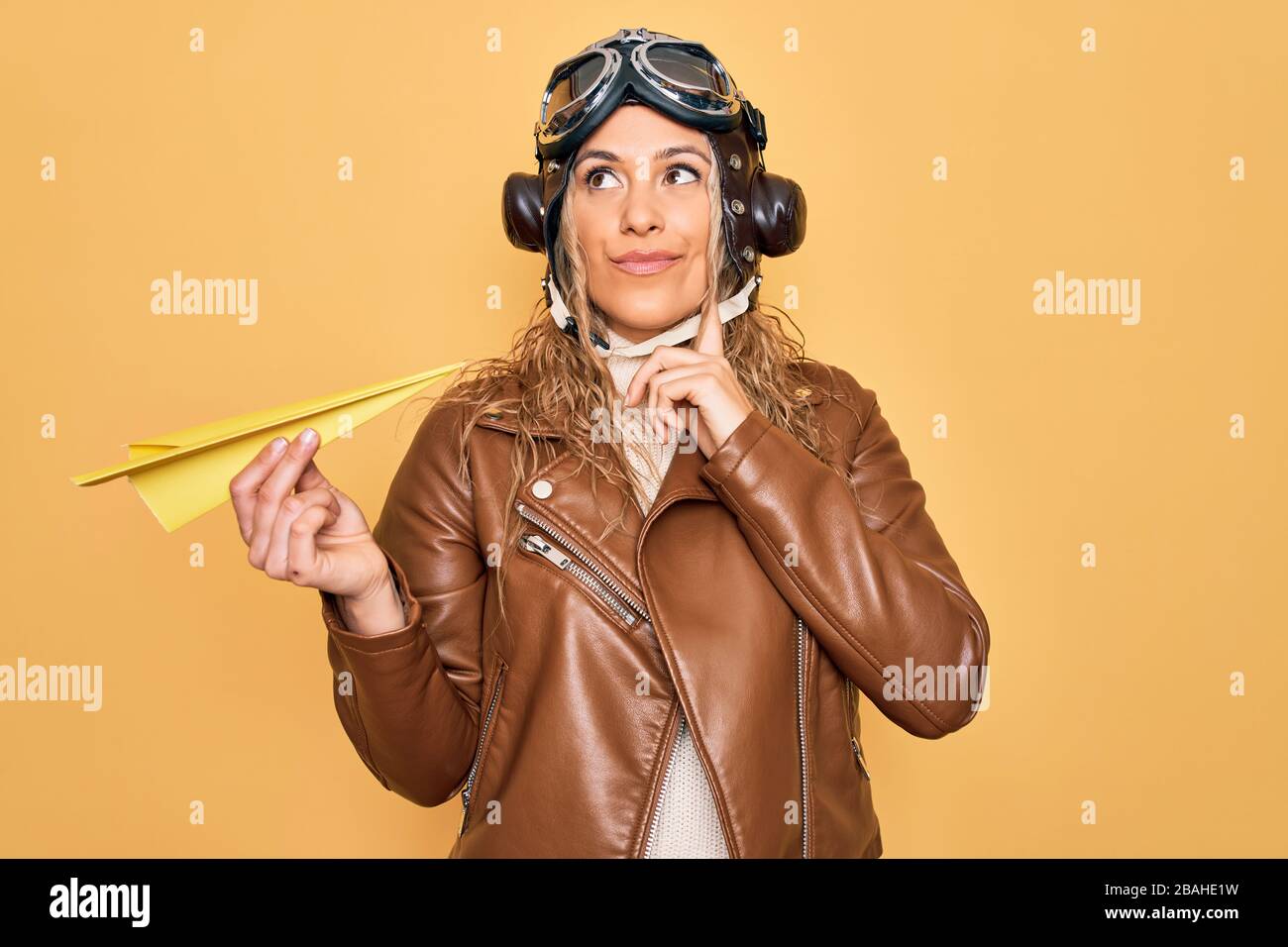 Beautiful blonde aviator woman wearing vintage pilot helmet whit ...