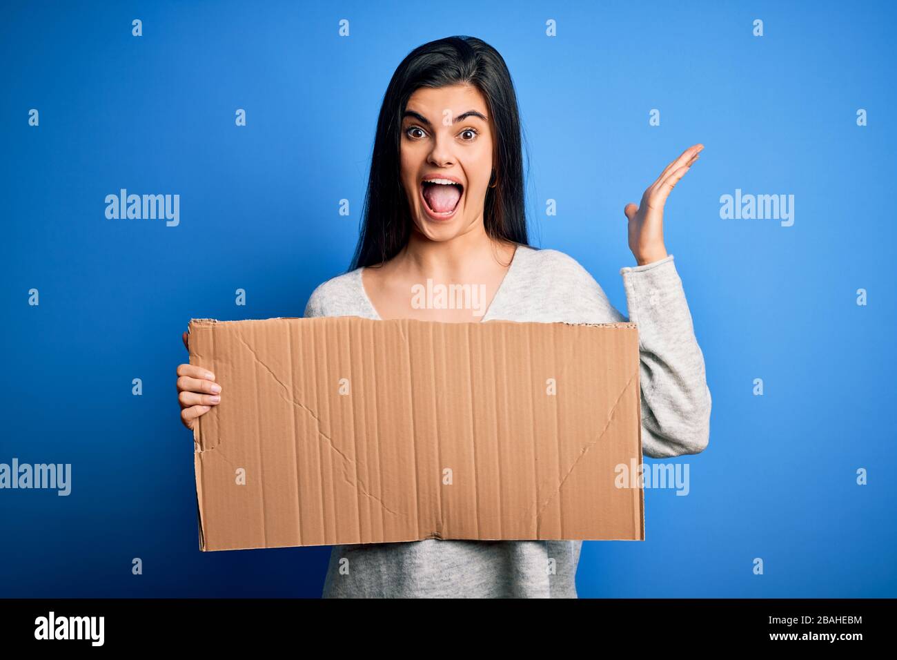 Young beautiful brunette activist woman holding blank cardboard banner ...
