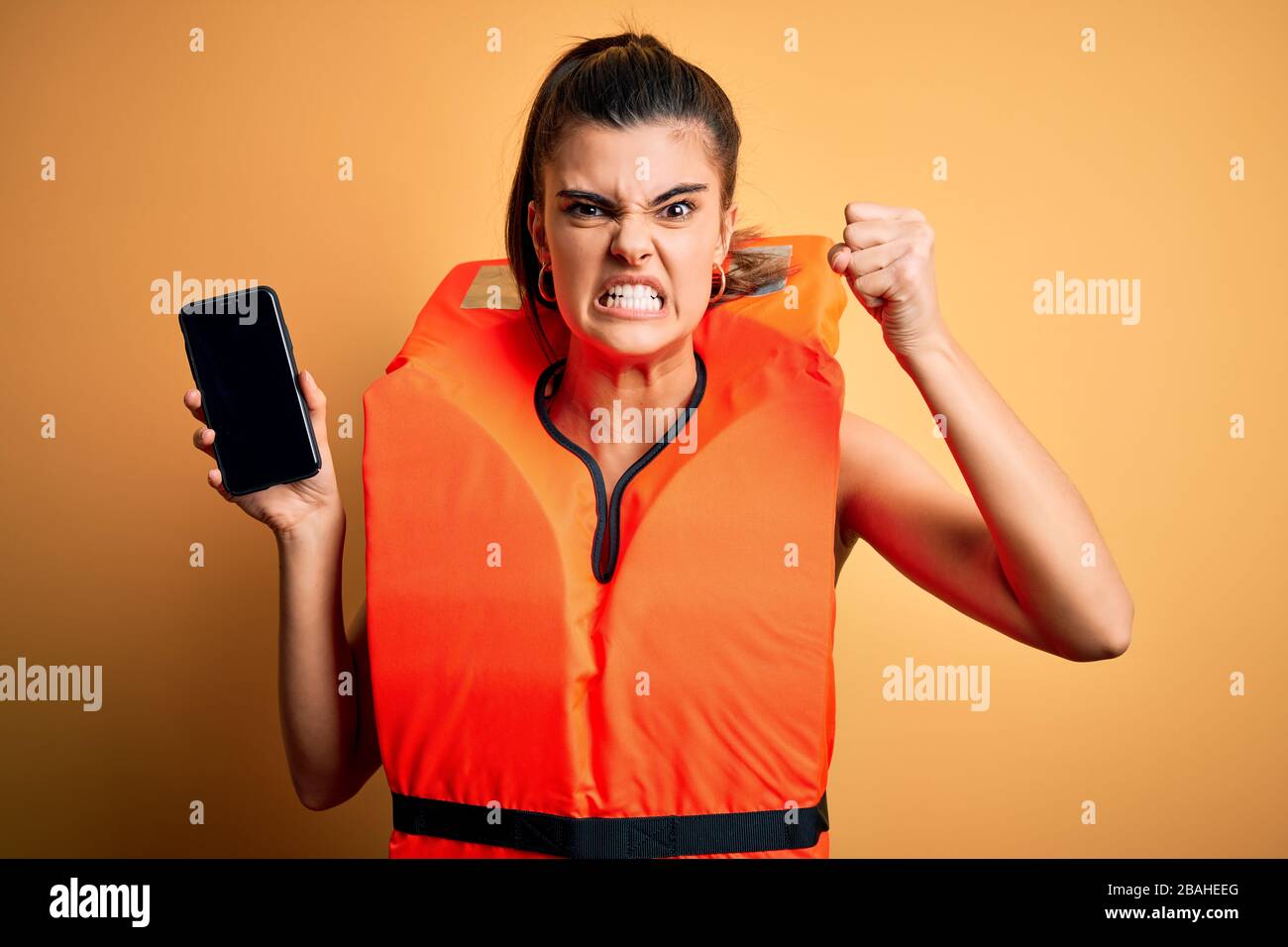 Young beautiful brunette woman wearing safe lifejacket showing ...