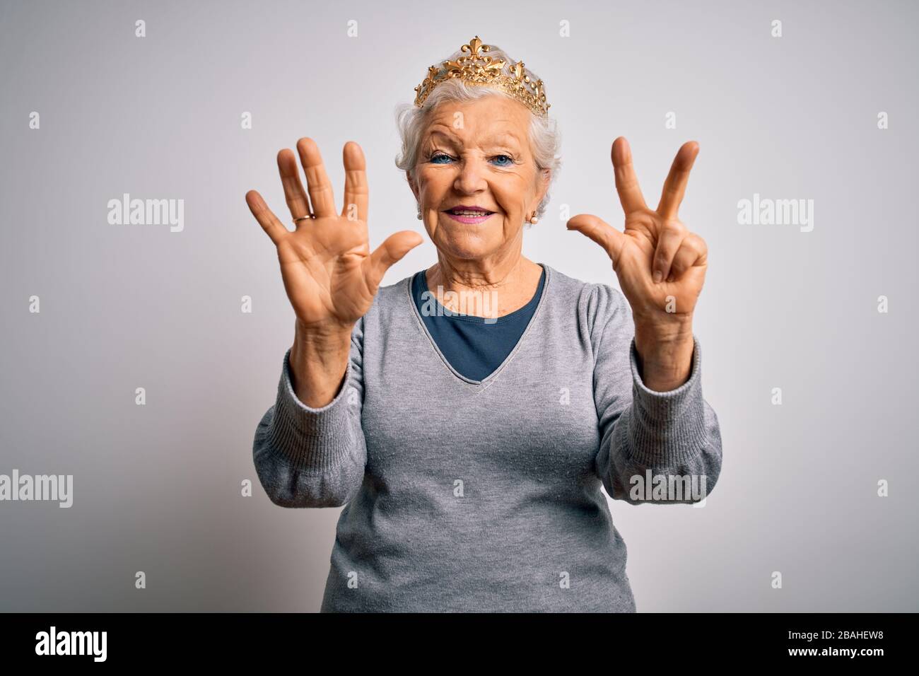Senior beautiful grey-haired woman wearing golden queen crown over ...