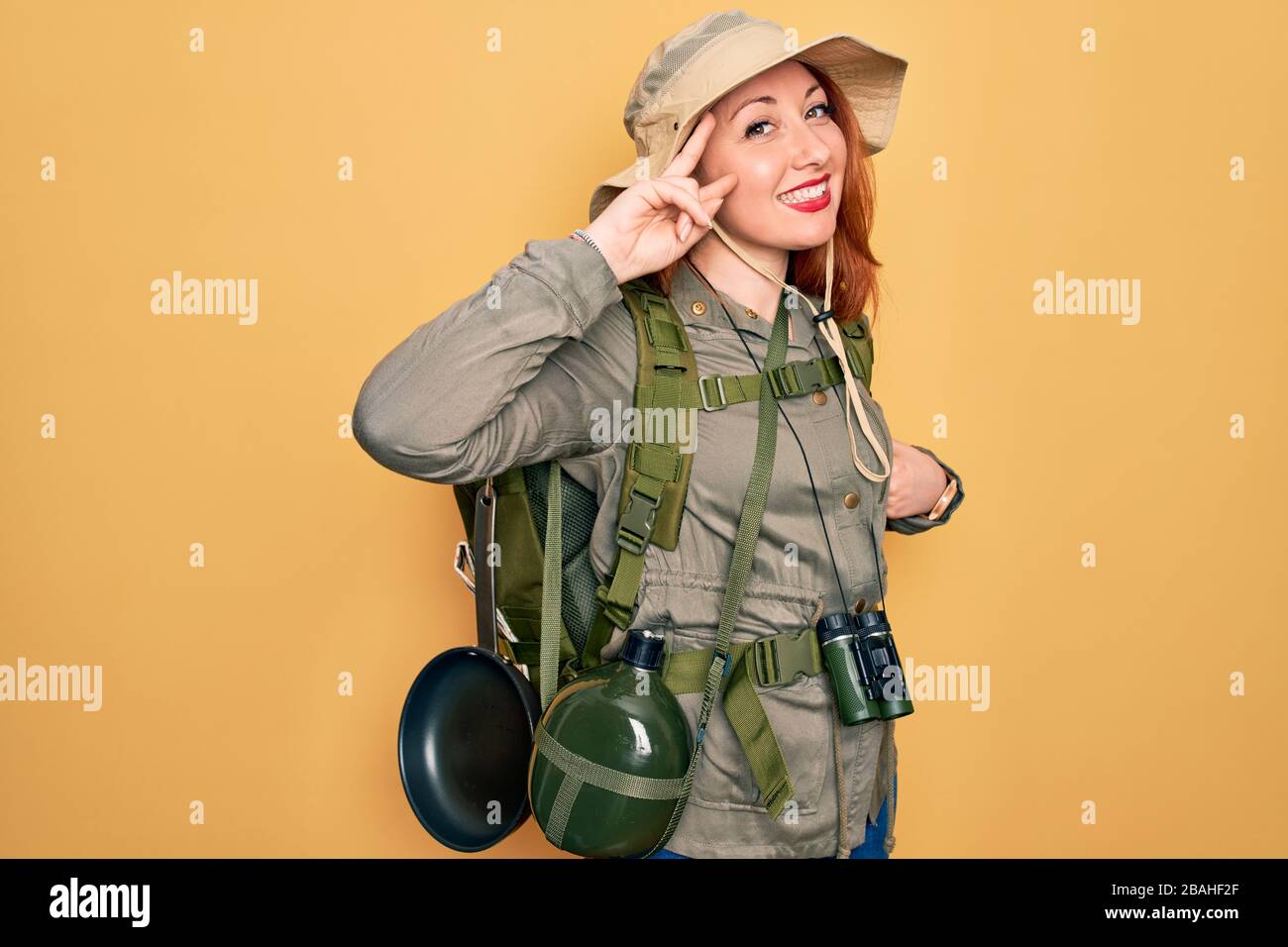 Young redhead backpacker woman hiking wearing backpack and hat over ...