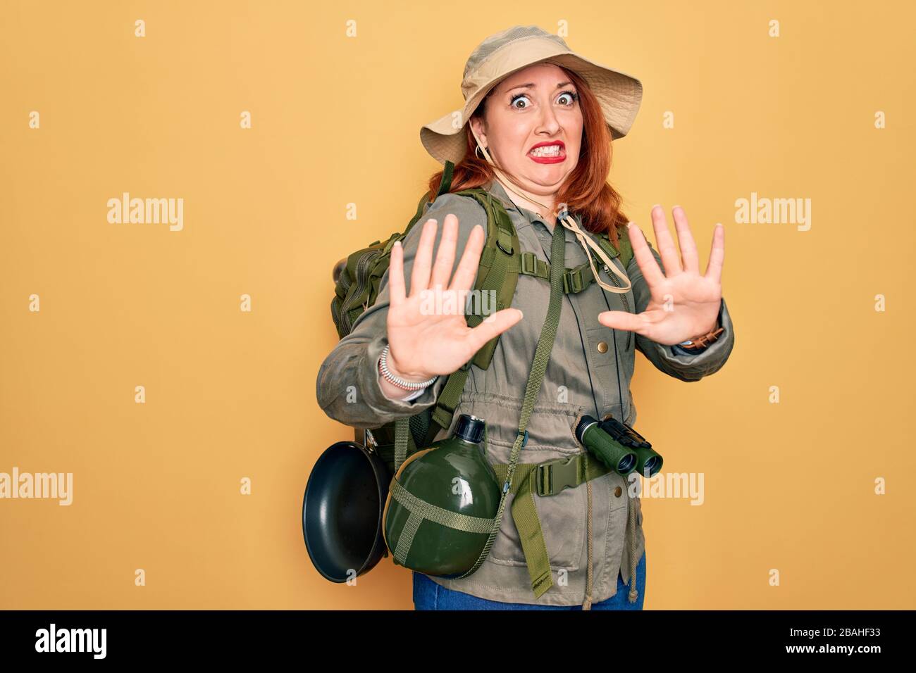 Young redhead backpacker woman hiking wearing backpack and hat over ...