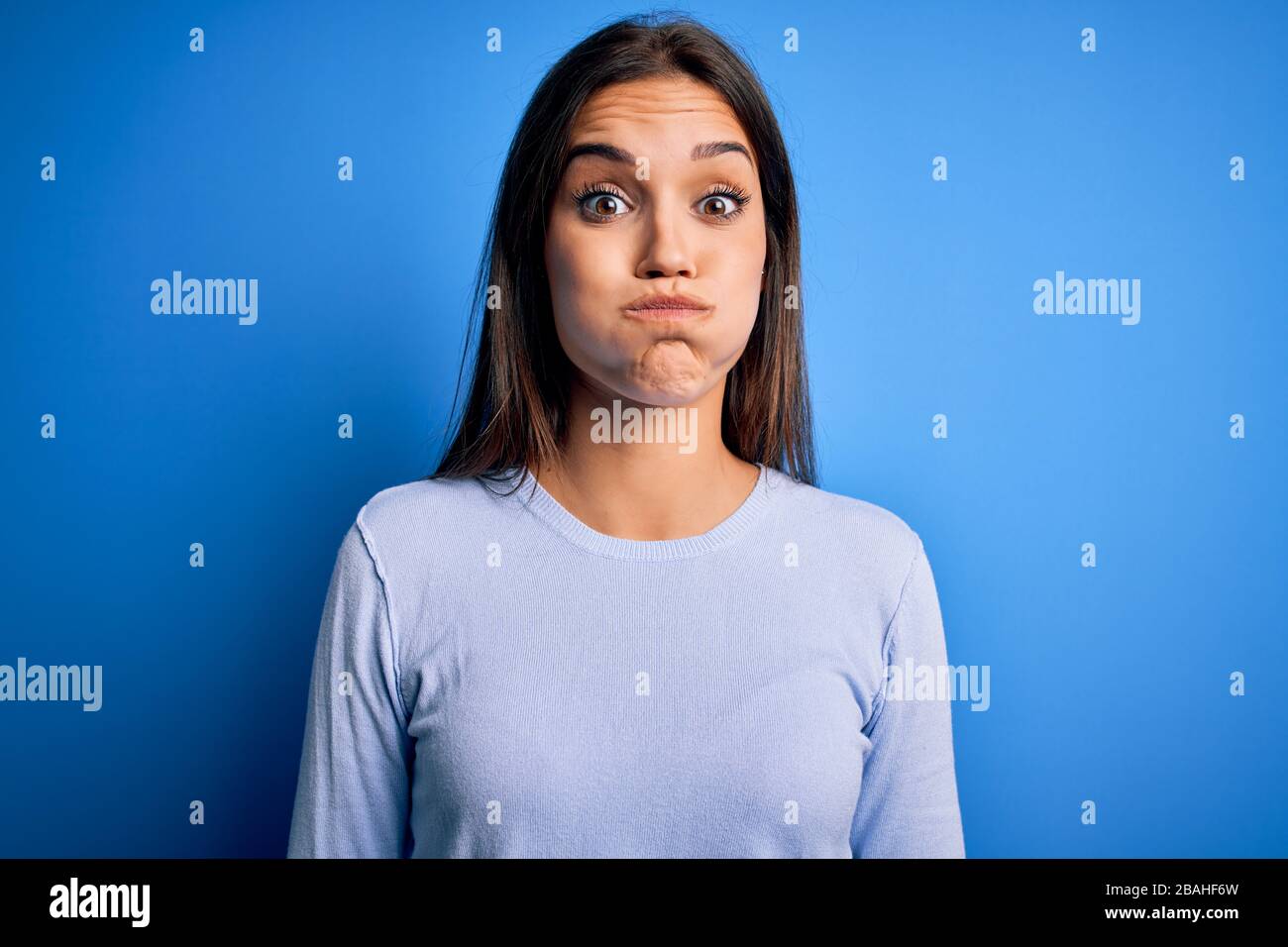 Young beautiful brunette woman wearing casual sweater standing over ...