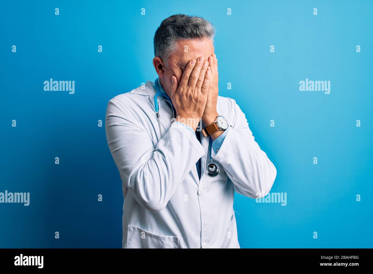 Middle age handsome grey-haired doctor man wearing coat and blue ...