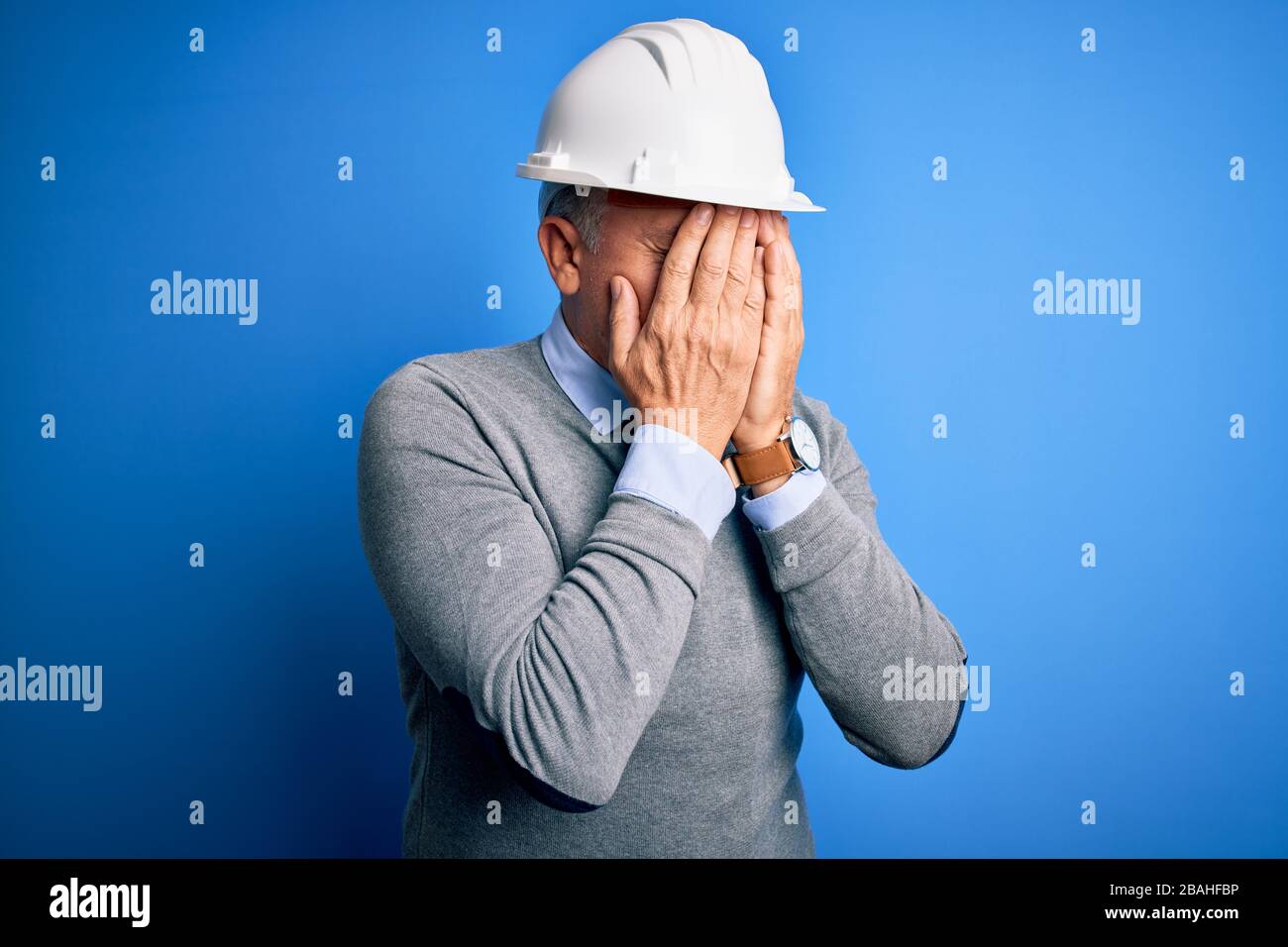 Middle age handsome grey-haired engineer man wearing safety helmet over ...