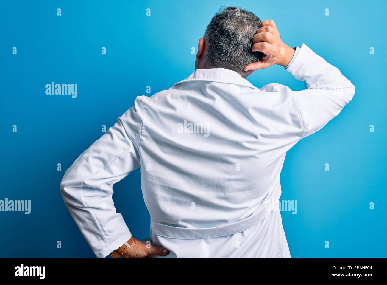 Middle age handsome grey-haired doctor man wearing coat and blue ...