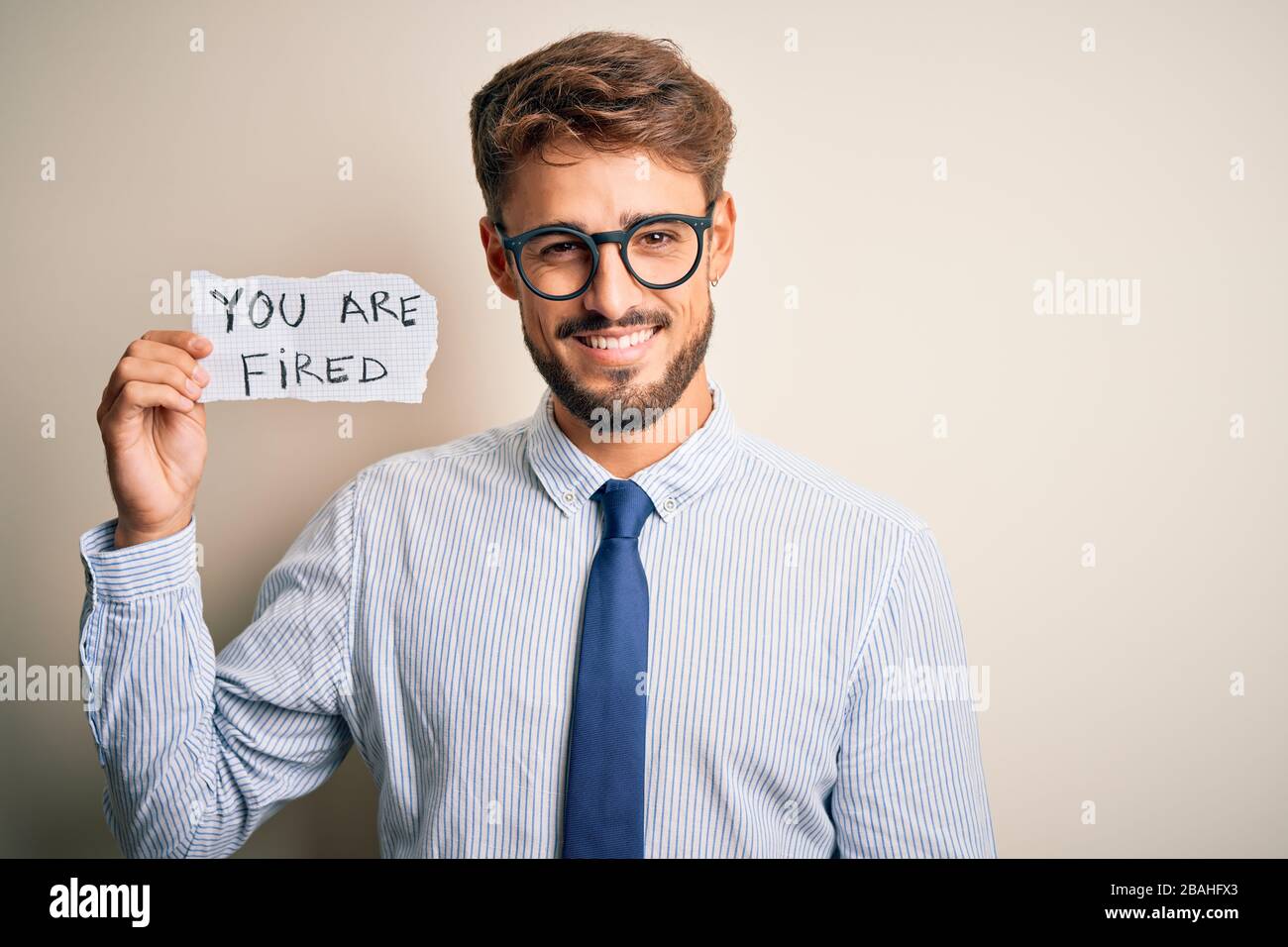 Young businessman wearing glasses holding paper with you are fired ...
