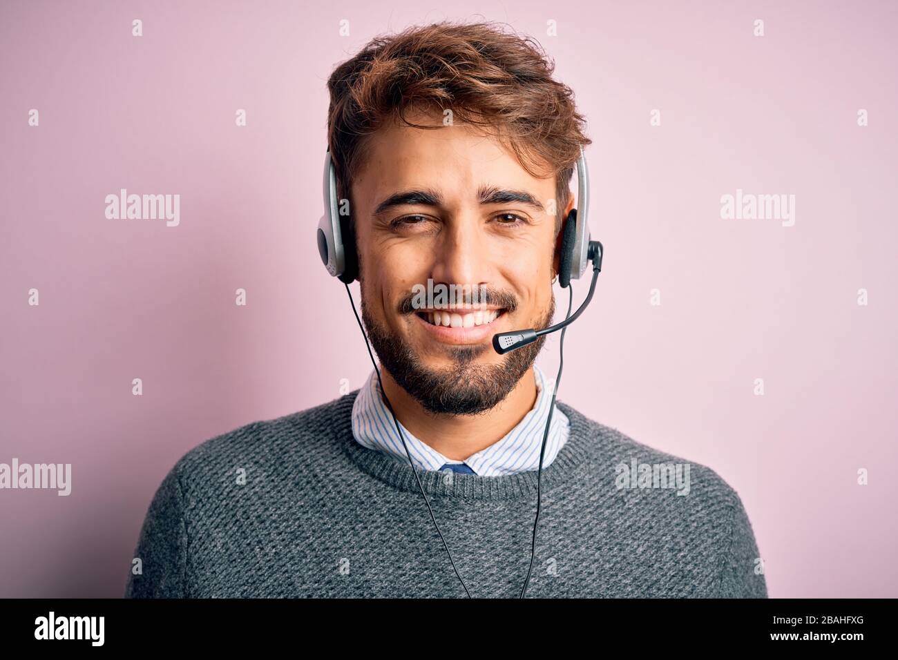 Young call center agent man with beard wearing headset over isolated ...