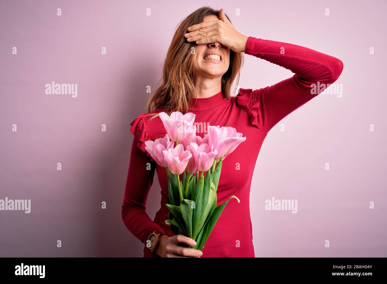 Young beautiful brunette woman holding bouquet of pink tulips over ...