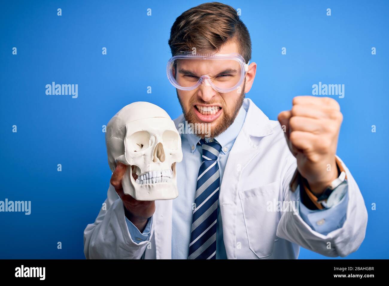 Young blond doctor man with beard and blue eyes wearing coat and ...