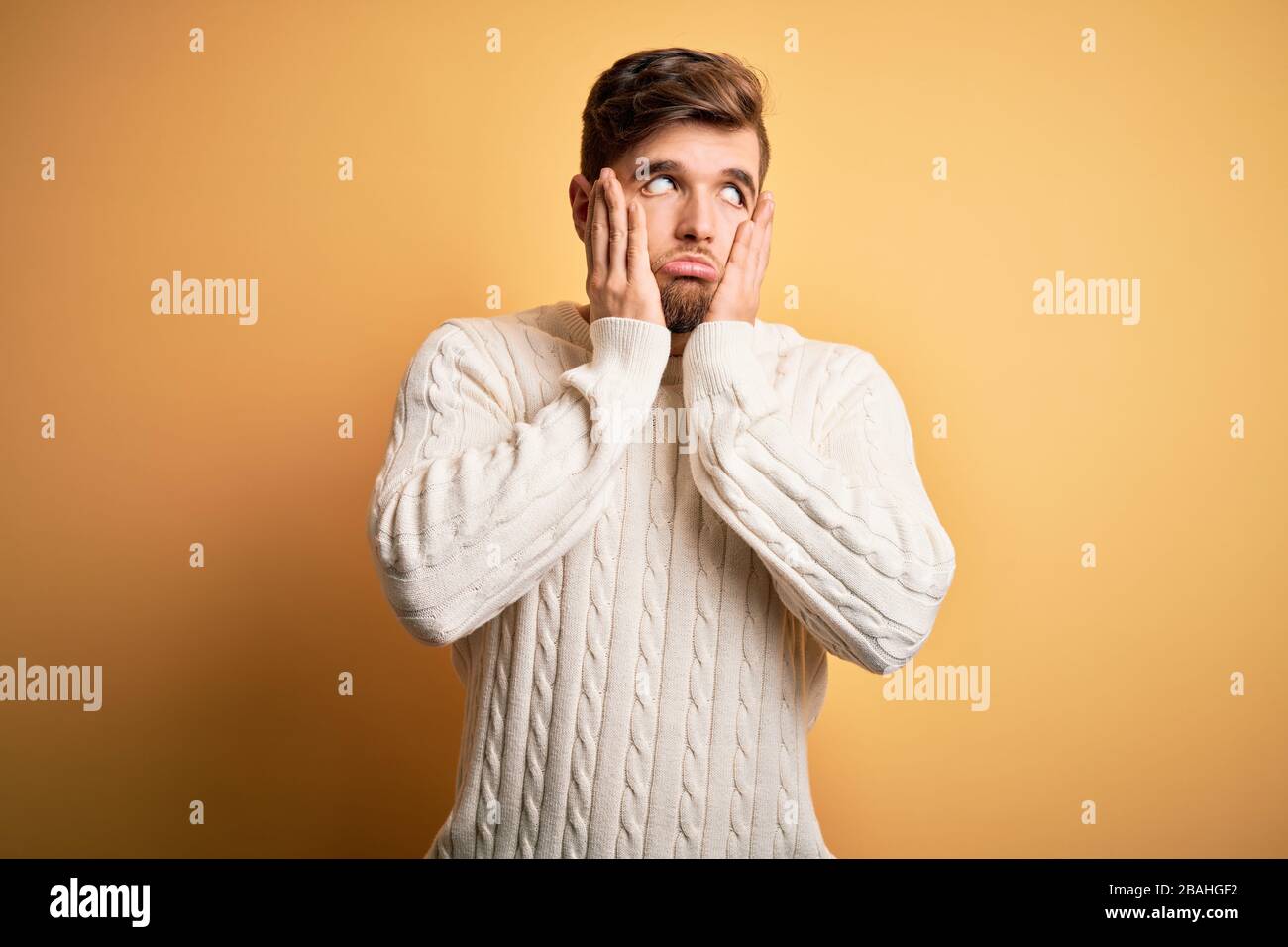 Young blond man with beard and blue eyes wearing white sweater over ...