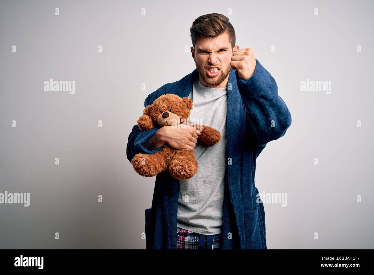 Young blond man with beard and blue eyes wearing pajama holding teddy ...