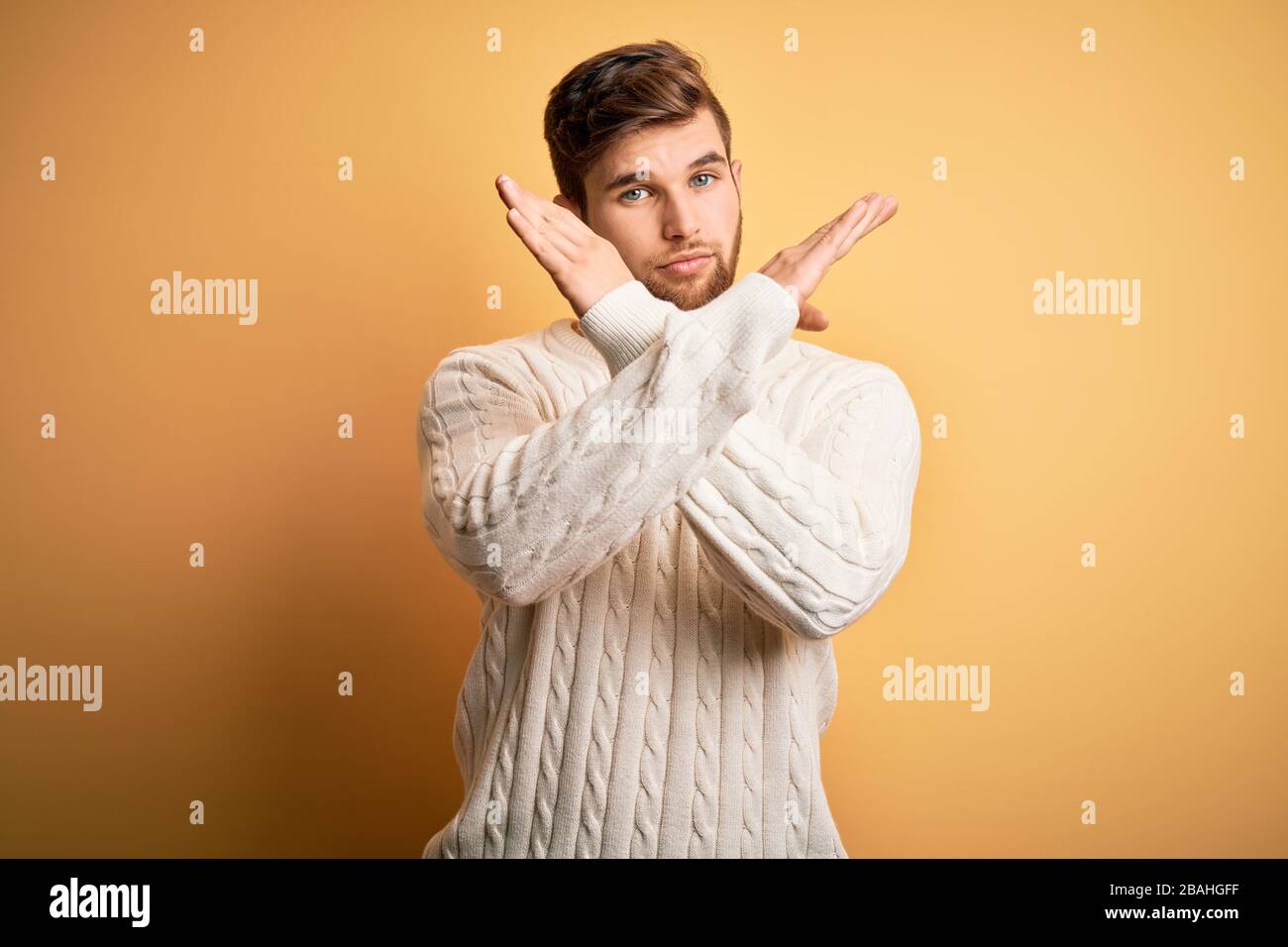 Young blond man with beard and blue eyes wearing white sweater over ...